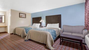 Quarto de hotel com duas camas, um sofá, uma mesa e um abajur.