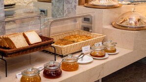 Um buffet com pães, doces e diversas geleias.
