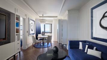 Uma sala de estar moderna com um sofá azul, uma área de jantar com mesa redonda e vista através de uma janela grande.