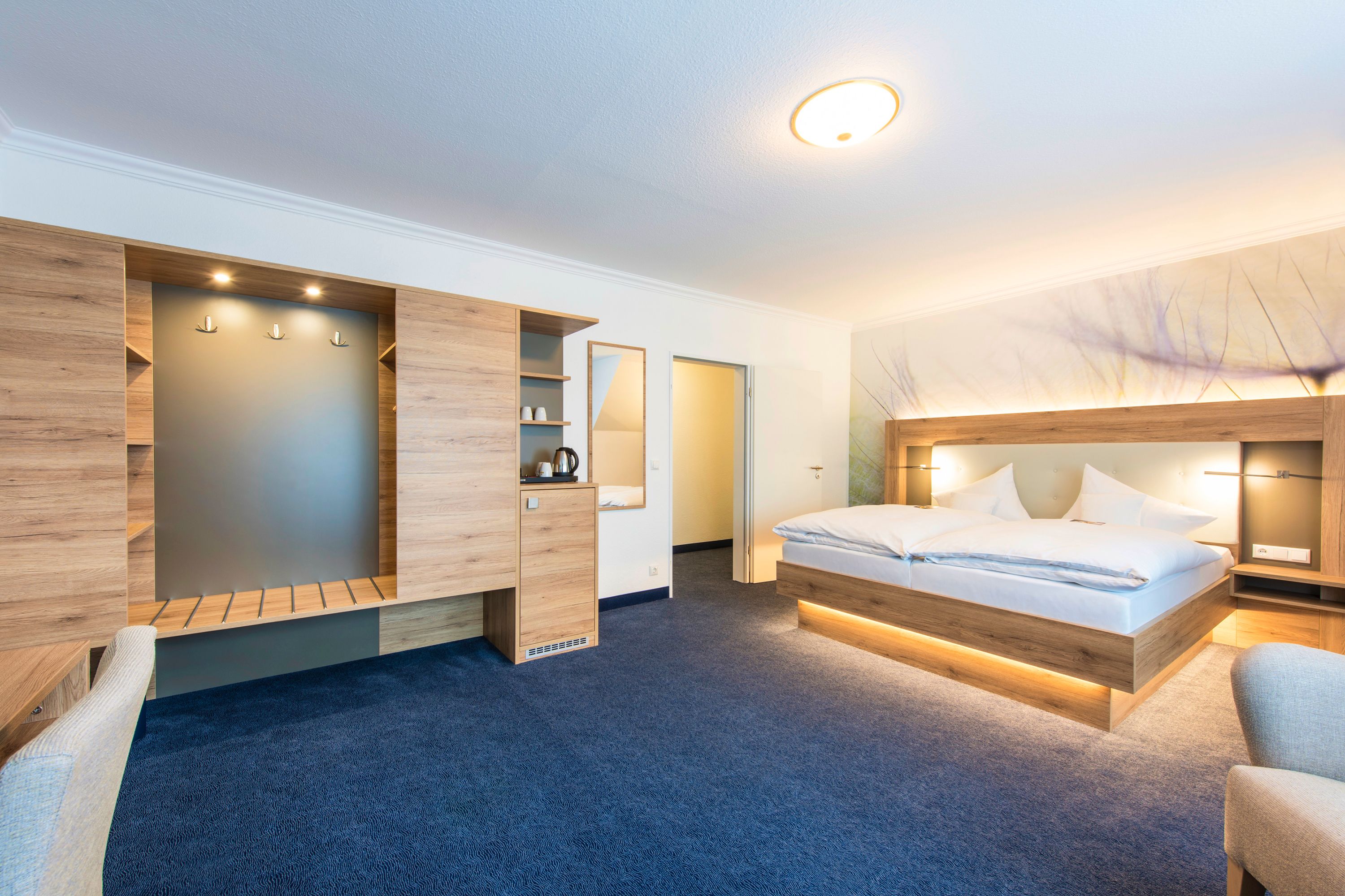 Quarto de hotel moderno com cama, armário embutido e área de estar.