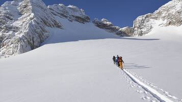 Uma trilha nevada na montanha com um grupo de pessoas caminhando.