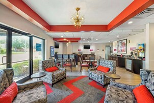 Um saguão de hotel com sofás estampados, uma área de bar e vista através de grandes janelas.