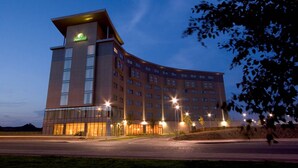 Um hotel moderno com fachada curva, vários andares e entrada destacada com portas de vidro.