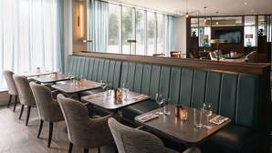 Um restaurante com um balcão comprido, cabines e cadeiras de vime.