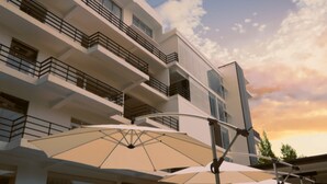 Um edifício moderno com várias varandas e grandes guarda-sóis.