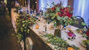 Uma longa mesa de banquete com arranjos florais e velas.