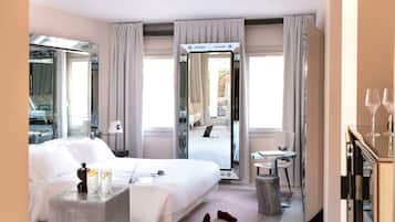 Quarto de hotel com cama, escrivaninha, cadeira, espelho e guarda-roupa.
