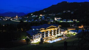 Um hotel com vários andares e piscina, rodeado por uma paisagem montanhosa.