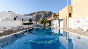 Piscina com design de tubarão, cadeiras de descanso e montanhas ao fundo.