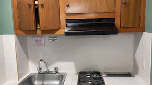 Uma cozinha com armários de madeira, pia de aço inoxidável, fogão a gás e lava-louças.