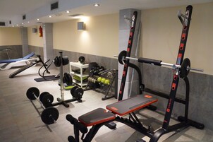 Uma academia com equipamentos de musculação, bancos e halteres.