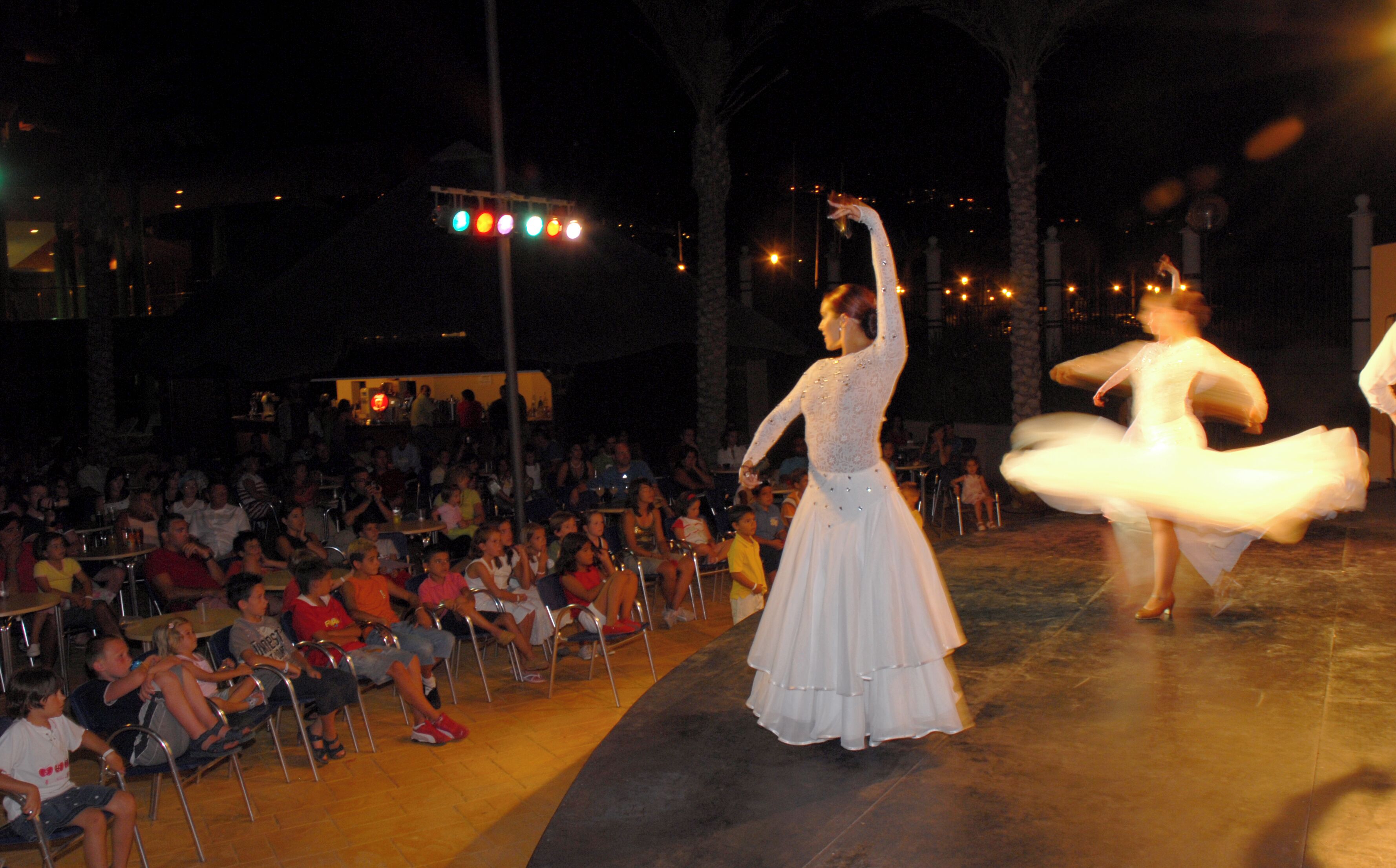 Apresentação de dança num palco com plateia sentada em cadeiras.