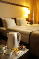 Quarto de hotel com cama, mesa de cabeceira com cafeteira, chávenas e saquetas de chá.