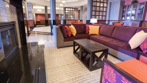 Um hall amplo com um sofá grande, uma mesa de centro e uma lareira.