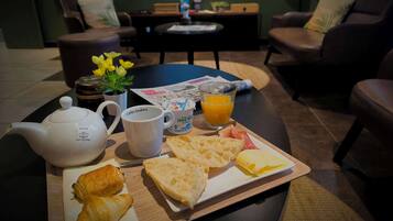 Bandeja de café da manhã com croissants, queijo e suco em uma mesa no quarto de hotel.