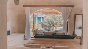 Quarto com uma cama grande, rede e vista para o oceano.