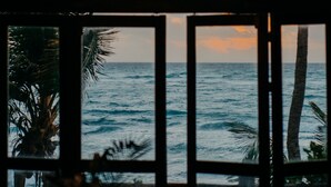 Quarto com vista para o oceano através de um design de janela geométrico.