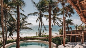Um deck de madeira com piscina, espreguiçadeiras e palmeiras, com vista para o oceano.