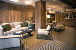 Um hall moderno com um sofá, poltronas, uma mesa de centro e um balcão de recepção.