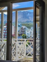 Vista de varanda com montanhas ao fundo, com edifícios e céu claro.