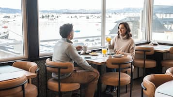 Um casal jantando em um restaurante com vista para uma paisagem nevada.