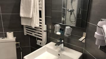 Uma casa de banho moderna com uma sanita branca, um porta-toalhas com uma toalha branca, um chuveiro com paredes de vidro e um espelho sobre a sanita.