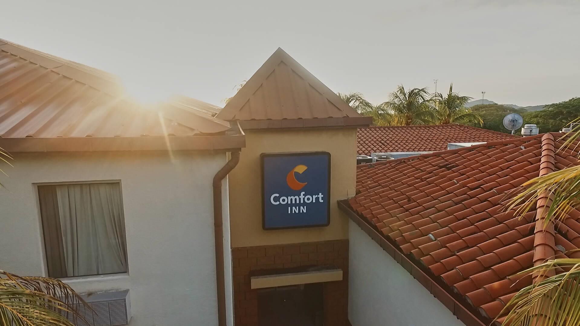Placa do Comfort Inn em um edifício com telhado de azulejos e pequena entrada.