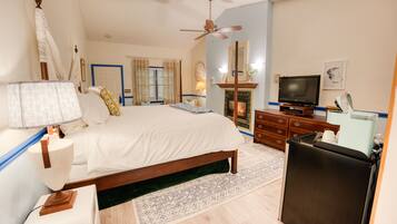 Quarto com cama, televisão, penteadeira, espelho e ventilador de teto.