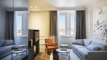 Uma sala de estar moderna com sofá, poltronas, mesa de centro e televisão.