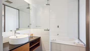 Uma casa de banho moderna com um espelho grande, uma sanita redonda, um chuveiro e uma banheira.