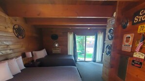 Um quarto de cabana acolhedor, com uma cama grande, uma mesinha e uma janela com cortinas.