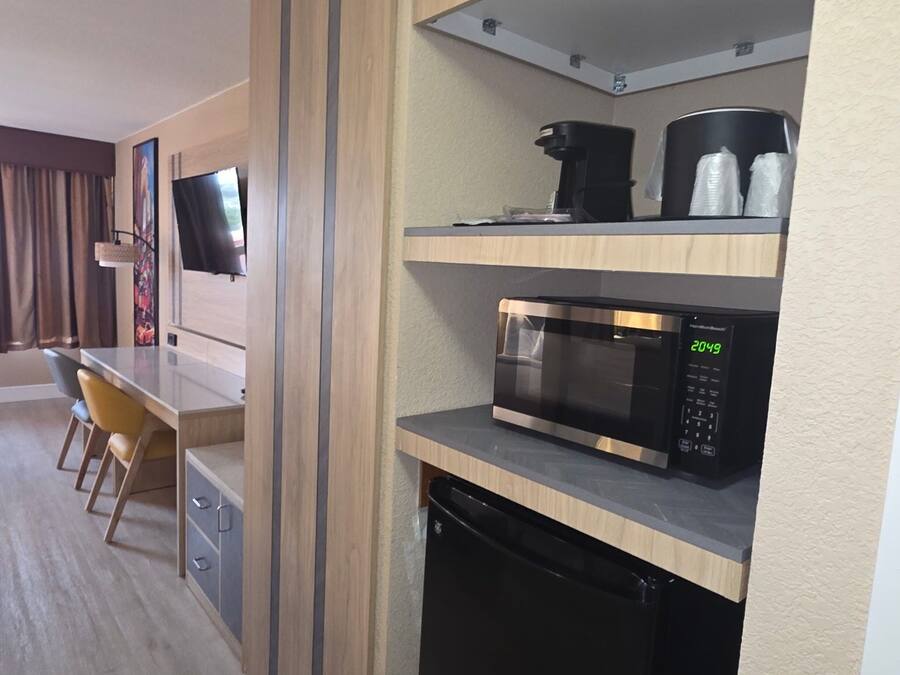 Uma cozinha moderna com micro-ondas, máquina de café e lava-louças. Possui uma área de refeições com mesa e cadeiras.