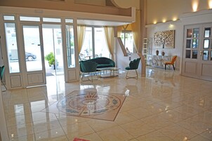 Um hall amplo com piso de azulejos, um sofá verde, uma mesa de centro de mármore e uma pintura na parede.
