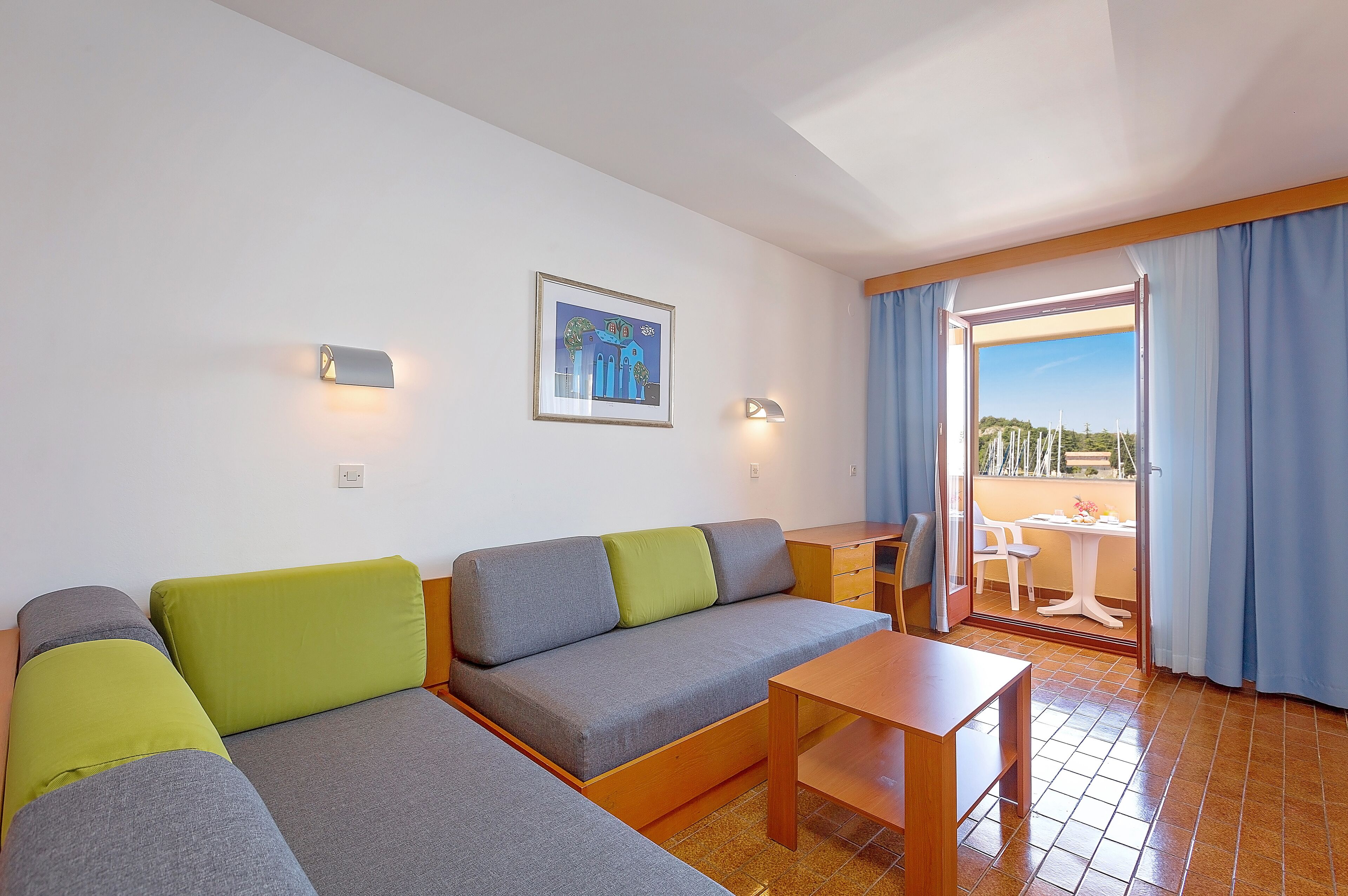Quarto moderno com sofá, mesa de madeira e varanda com vista.