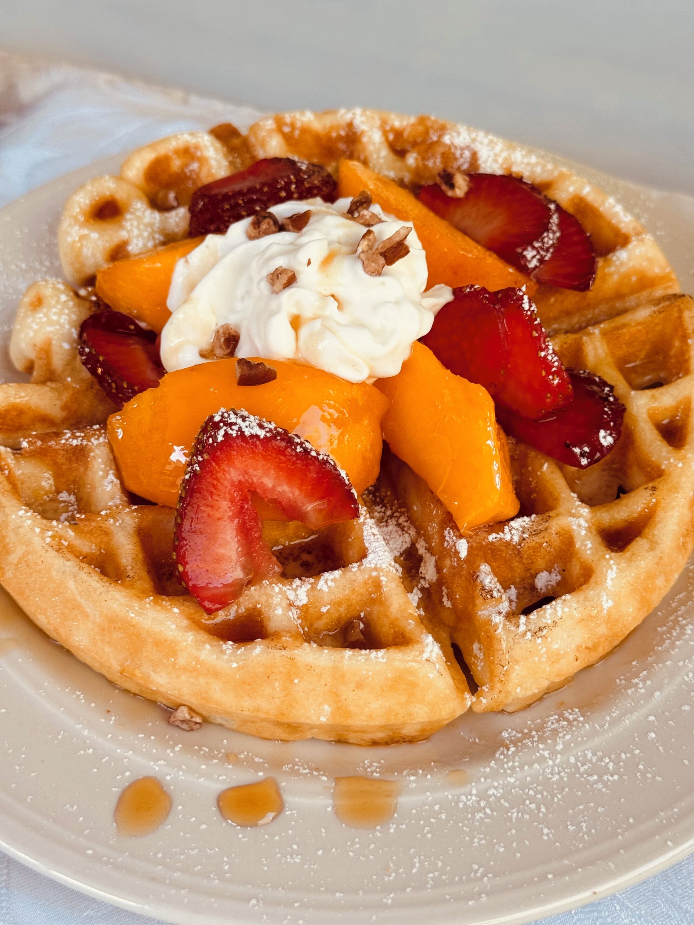 Waffle com fruta e chantilly em um prato.