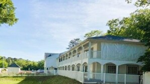 Um edifício de dois andares com fachada branca e varanda coberta.