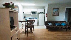 Um espaço de estar compacto com cozinha compacta, área de refeições e sofá.