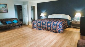 Um quarto com uma cama, um sofá, uma mesa de cabeceira e um abajur.