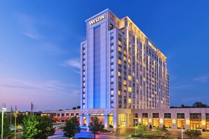 Um hotel moderno com um letreiro grande 'WESTIN', vários andares e uma entrada bem iluminada.