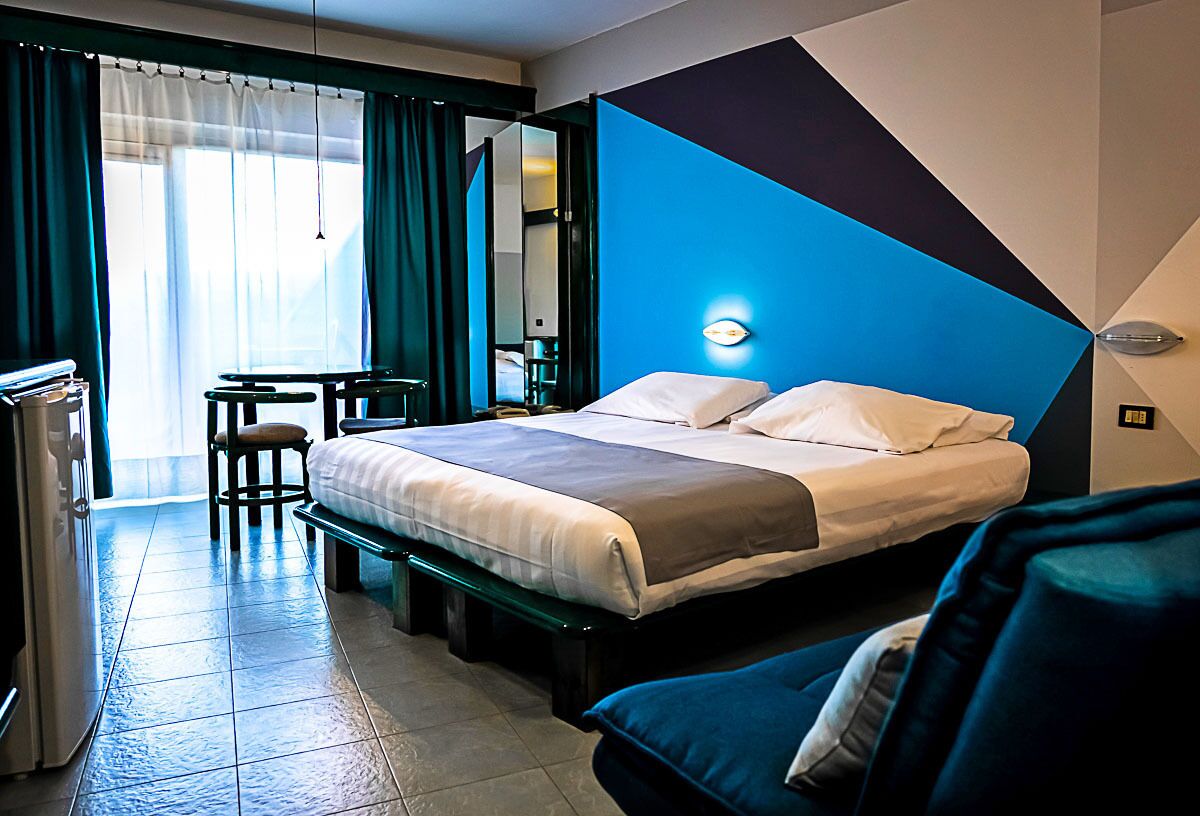Quarto de hotel com cama, secretária e cadeira.