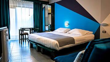 Quarto de hotel com cama, secretária e cadeira.