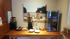 Uma mesa de madeira com uma máquina de café, um cesto e uma geladeira.
