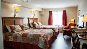 Quarto de hotel com duas camas, uma escrivaninha, uma cadeira e uma janela com cortinas.