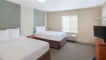 Quarto de hotel com duas camas, televisão, janela com persianas e piso coberto por carpete.