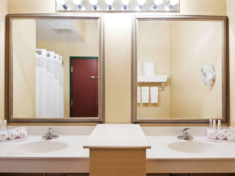 Casa de banho de hotel com duas pias, um espelho e um porta-toalhas.