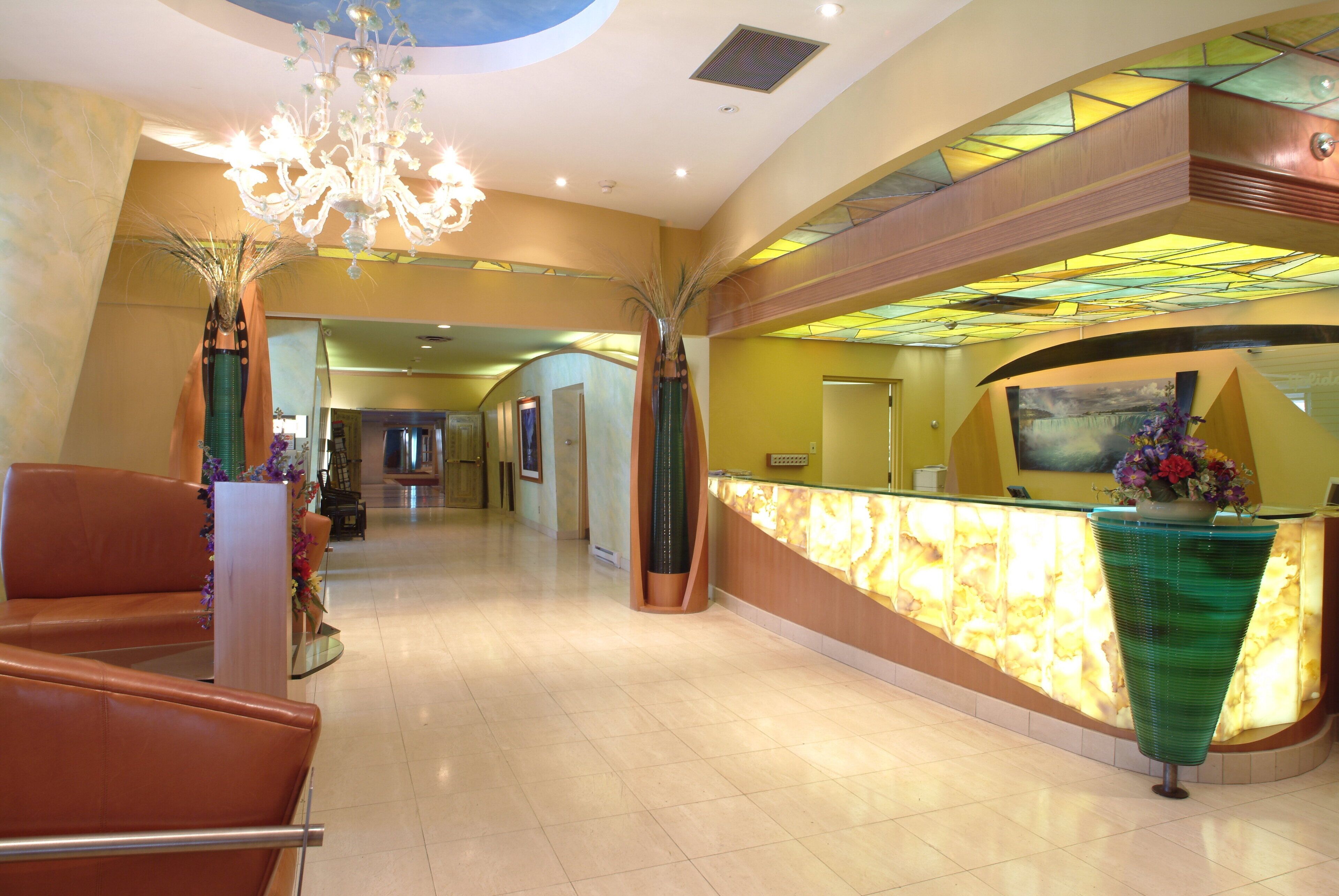 Um saguão de hotel com balcão de recepção, área de estar e um lustre.
