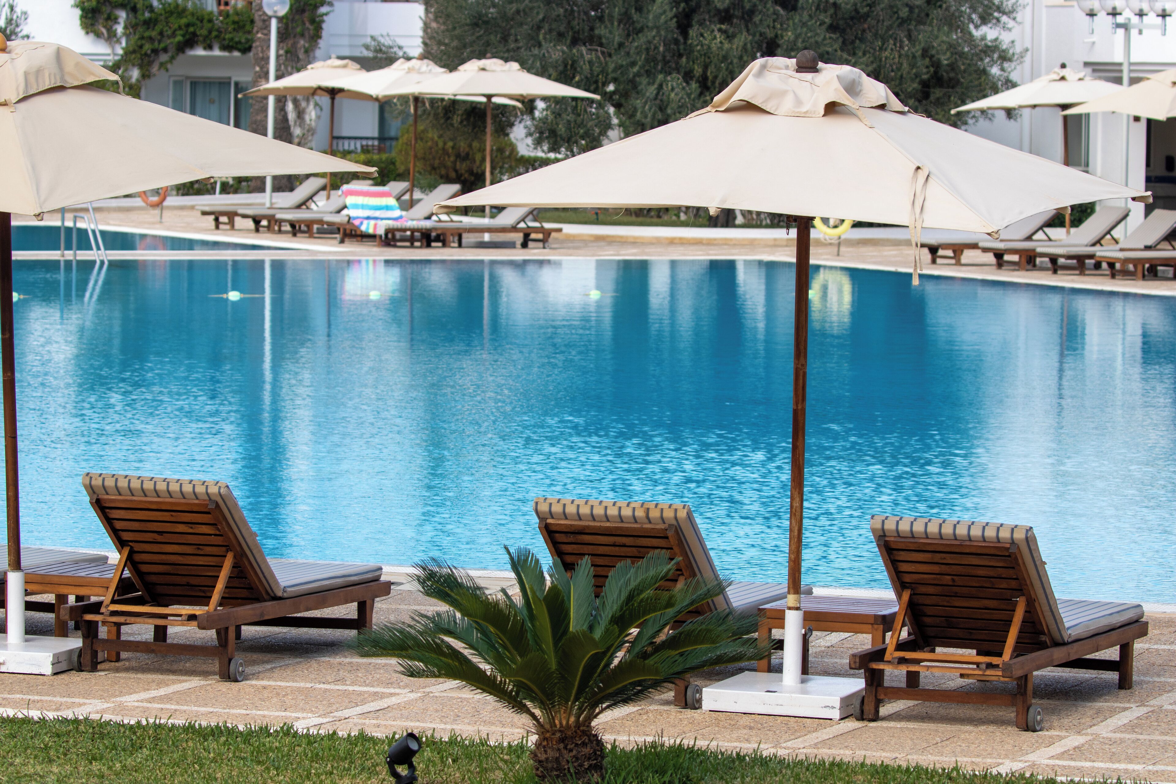 Uma área de piscina com espreguiçadeiras e guarda-sóis.