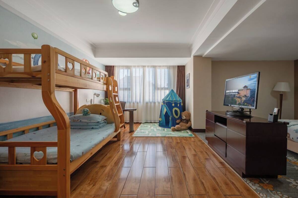 Um quarto com uma cama beliche, uma escrivaninha, uma televisão e uma pequena tenda infantil.