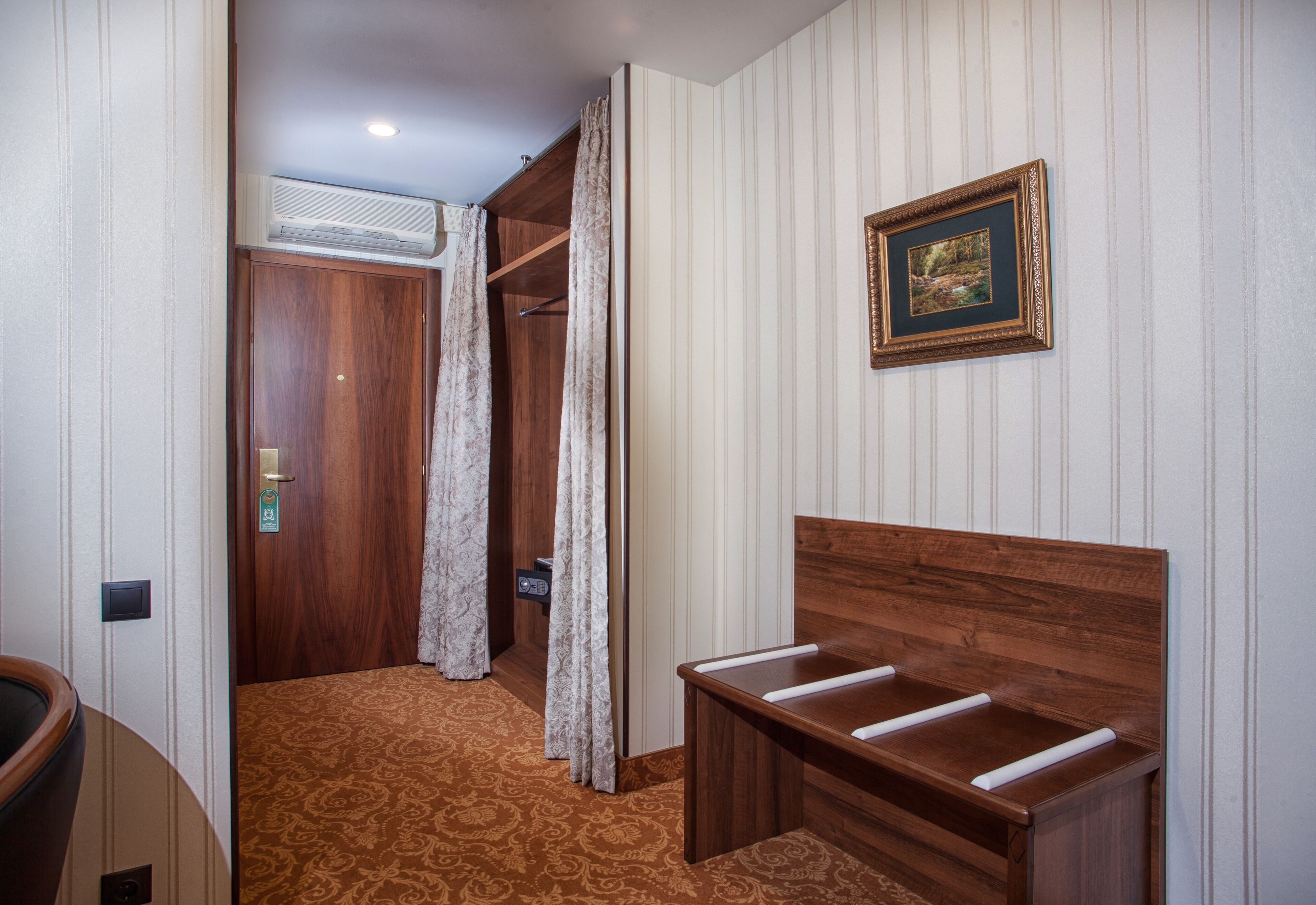 Quarto de hotel com cama de madeira, um guarda-roupa e um aparelho de ar condicionado.