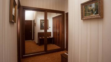 Um corredor com porta de madeira, um banco e um quadro na parede.